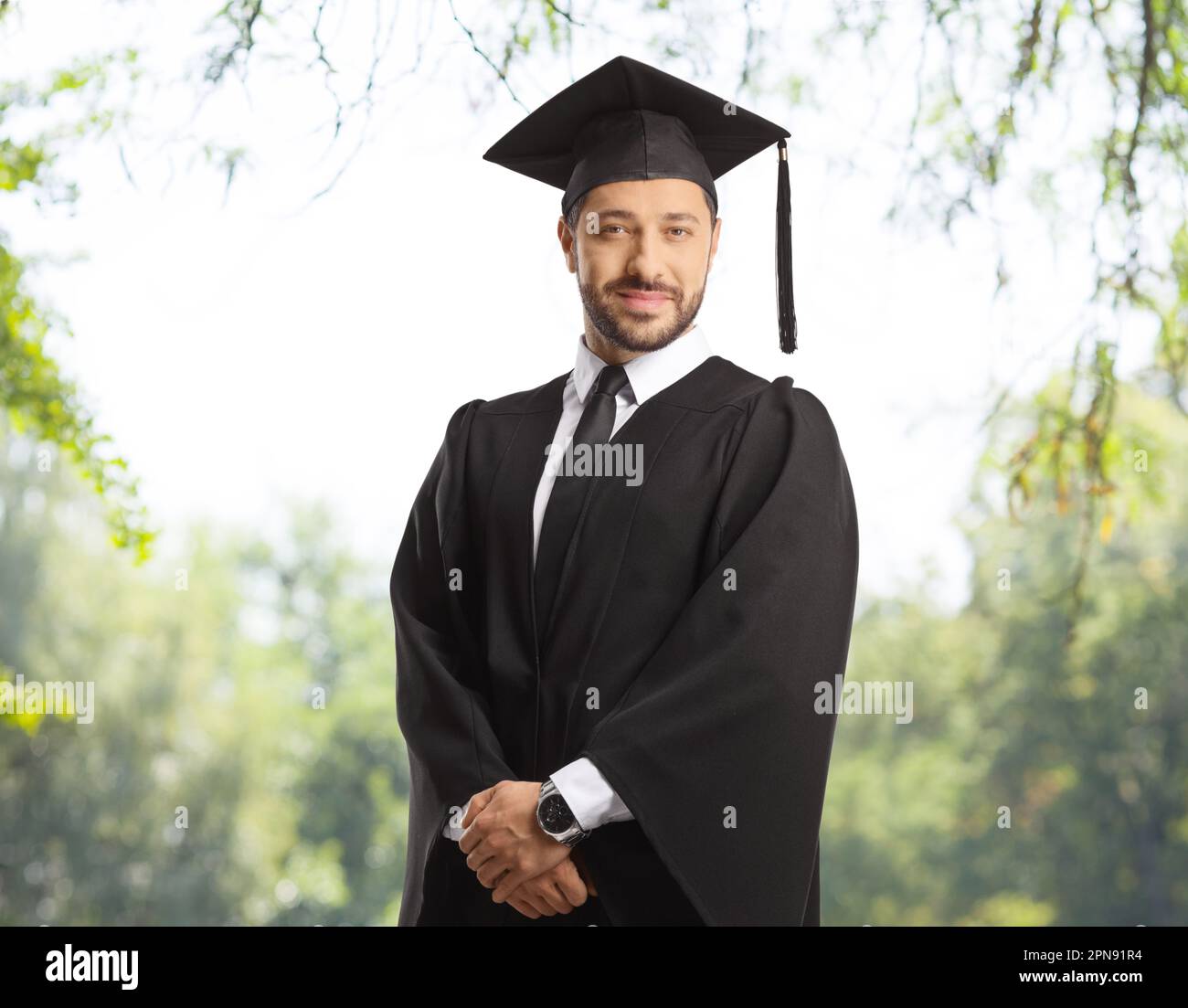 Man wearing a graduate gown and posing outdoors in a park Stock Photo ...