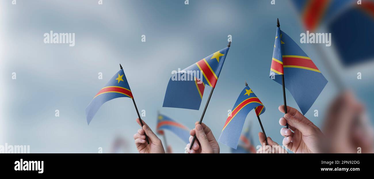 A group of people holding small flags of the Democratic Republic of the ...