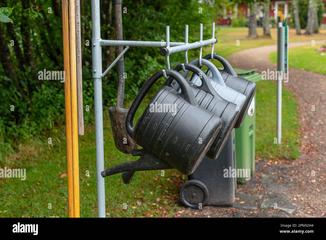 Water cans hanging in a row at a graveyard Stock Photo - Alamy