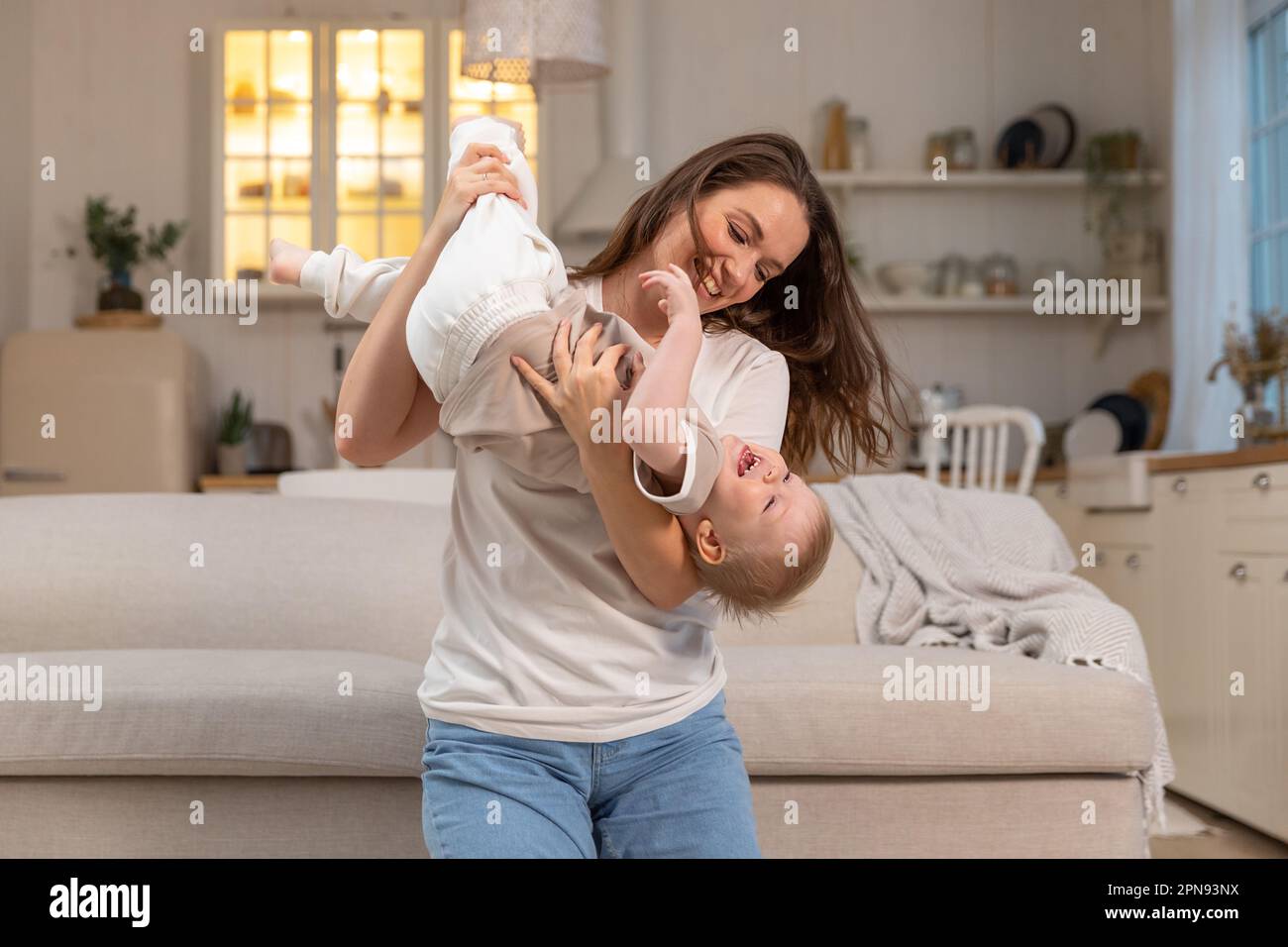 Happy family at home. Mother lifting in air little toddler child son. Mom and baby boy playing ...