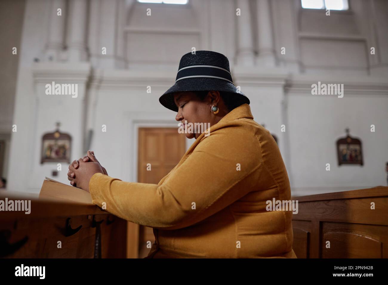 Side view of African American plump woman sitting on bench with Bible ...