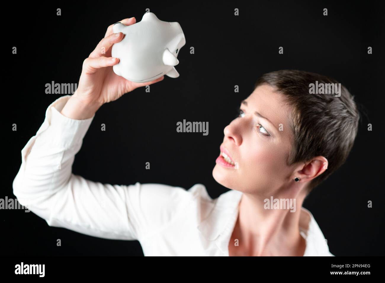 Empty white porcelain piggy bank held upside down by woman in business ...