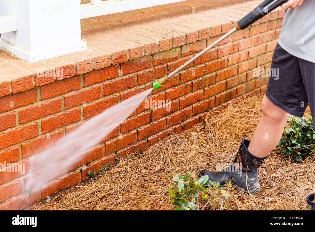 Person using a pressure washer to clean mold and mildew off brick ...
