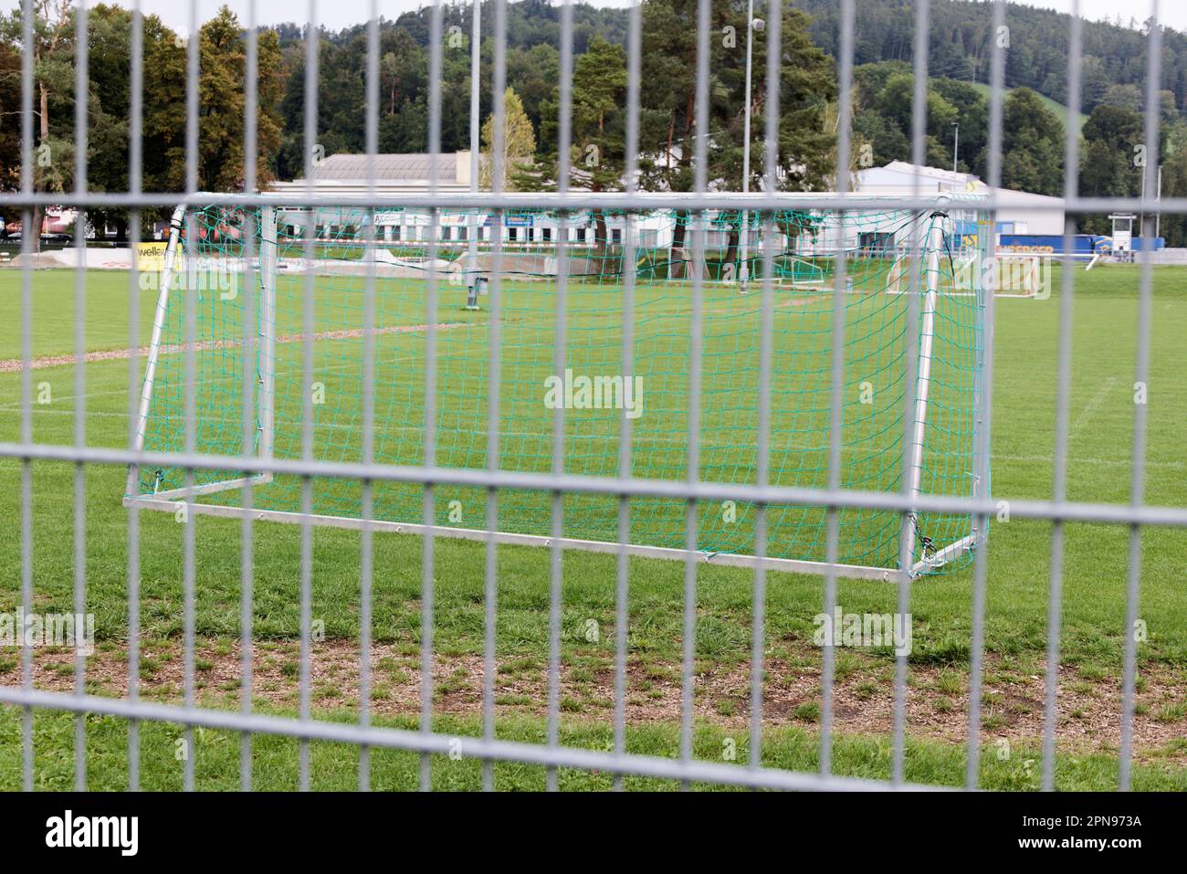 soccer goal on green meadow behind a barrier. editorial. day cloudy ...