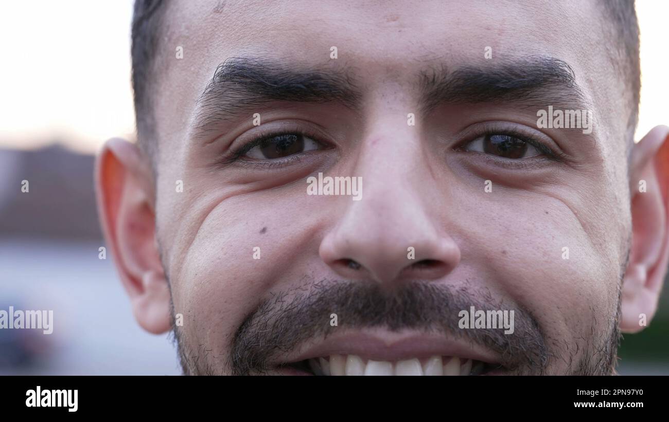 One Middle Eastern young man close up face and eyes smiling at camera ...