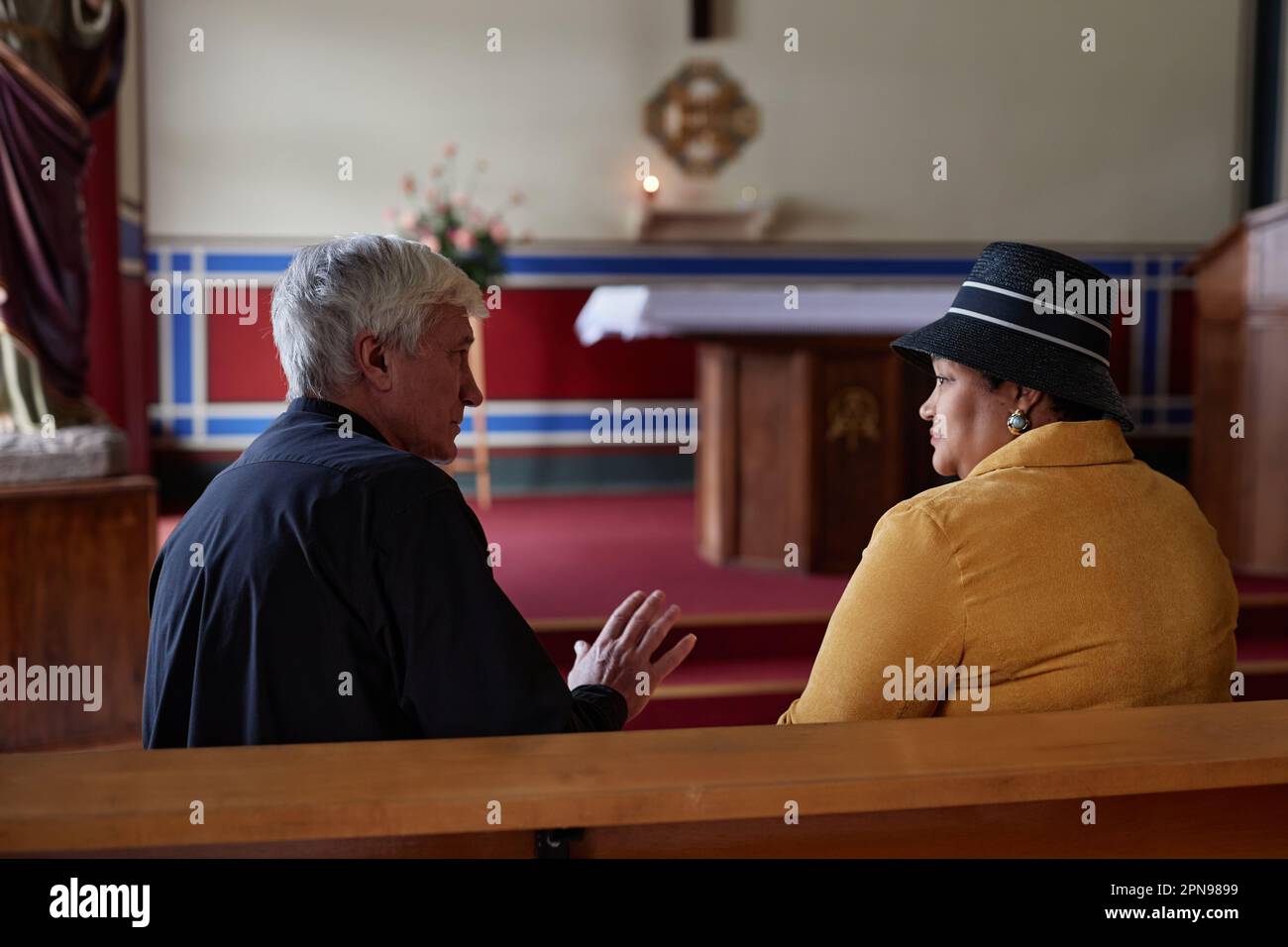 Rear view of senior priest discussing the ceremony with woman while ...