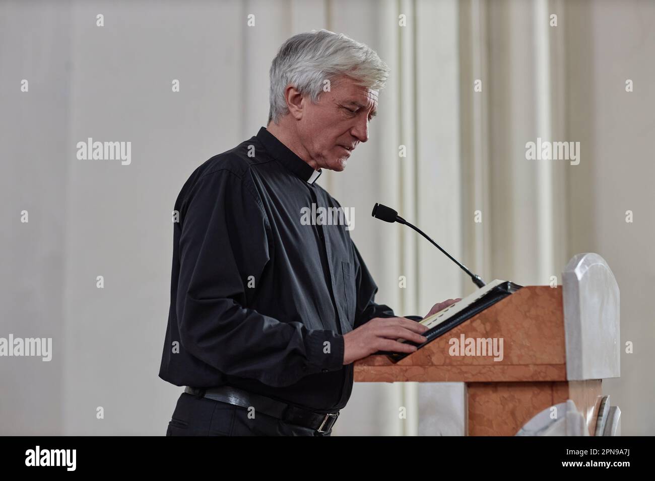 Senior priest standing behind the altar and reading sermon in ...