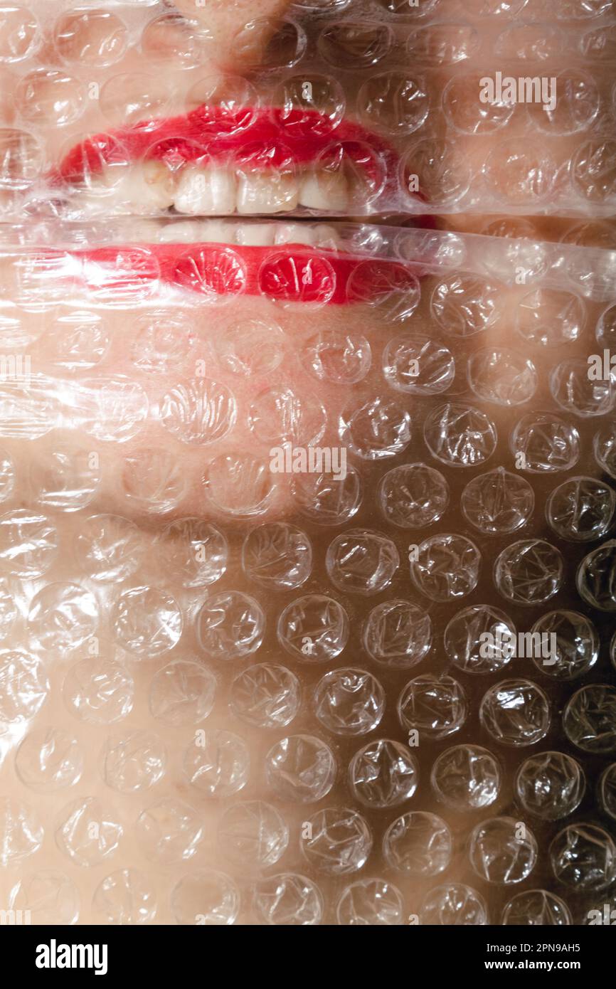 Portrait of a young girl with red lips with lipstick suffocates under a ...