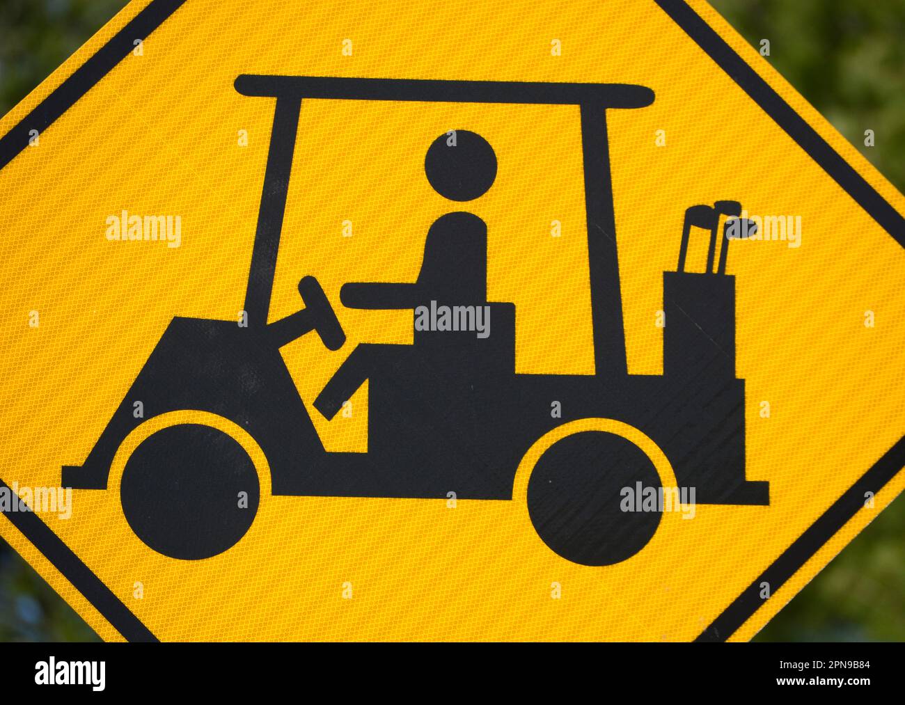 A golf cart crossing sign along a road warns motorists to watch for ...