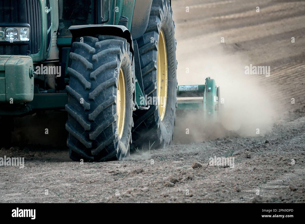 Tractor ploughing a field shrouded in the dust of dry soil from the ...
