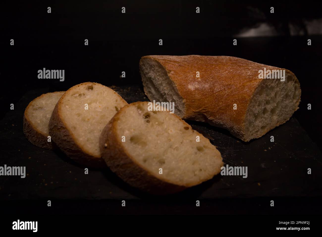Slices of bread with crumbs on a black board background. Front view ...