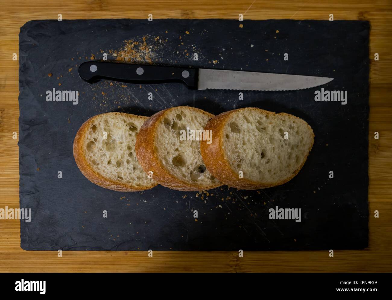 Slices of bread with crumbs on a black board background. Front view ...