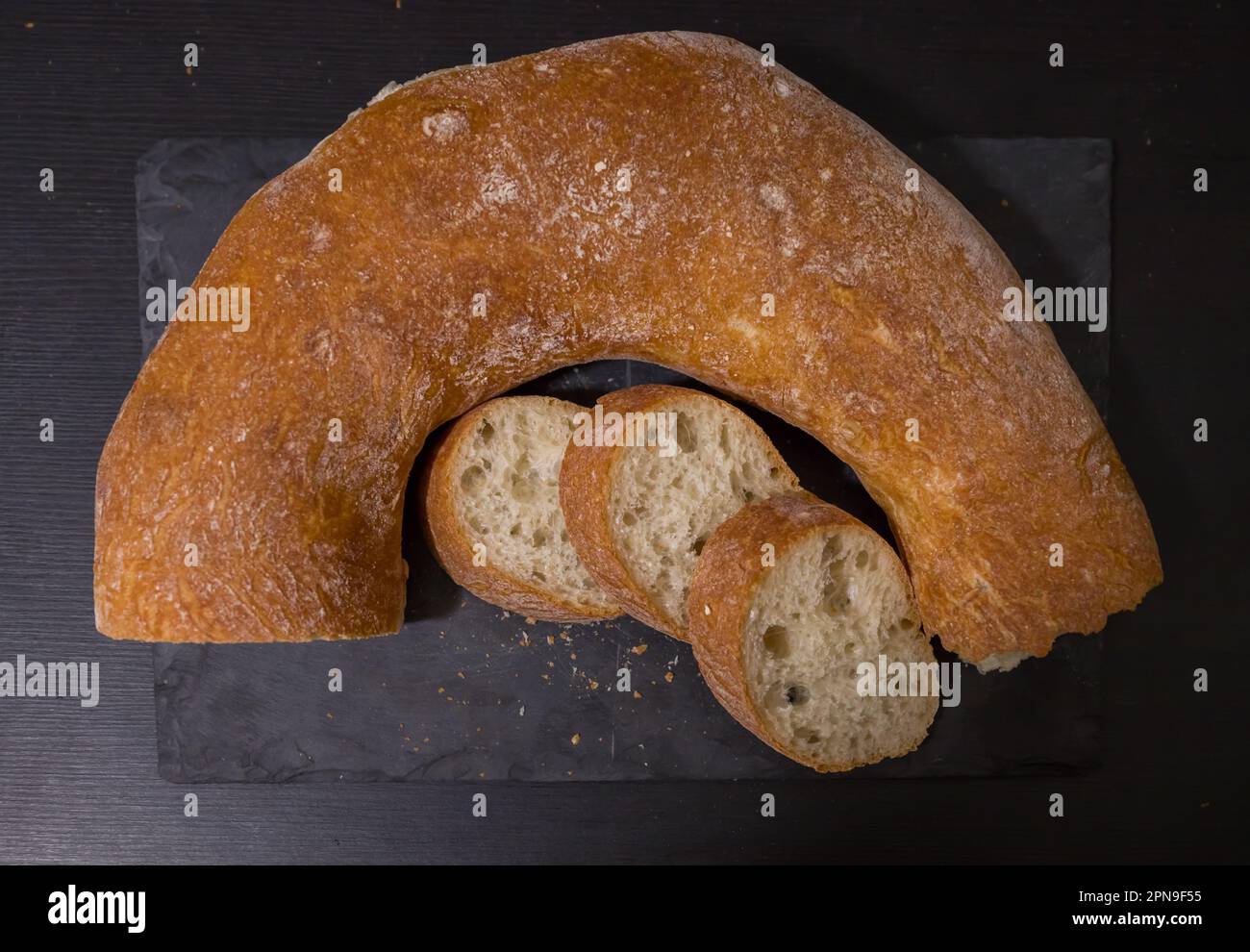 Slices of bread with crumbs on a black board background. Front view ...