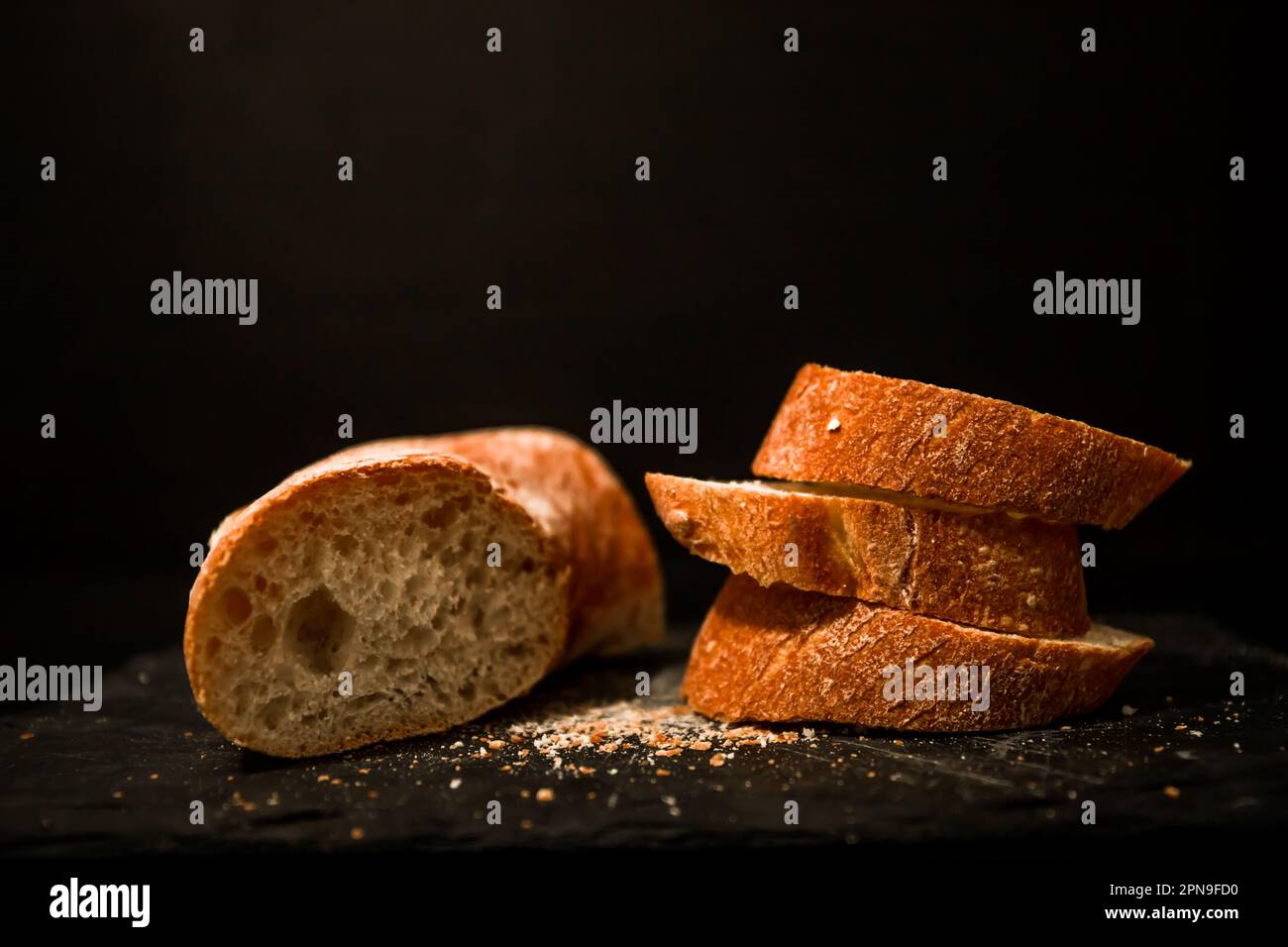 Slices of bread with crumbs on a black board background. Front view ...