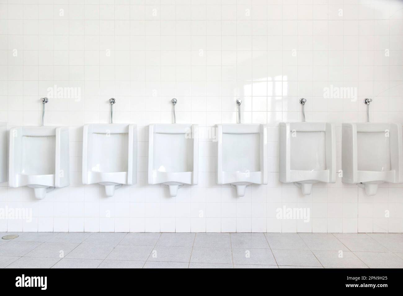 Row of white porcelain urinals and tiles in a toilet in Portugal Stock ...