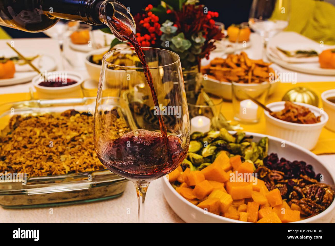 Red wine pouring into a glass standing on Thanksgiving dinner party ...