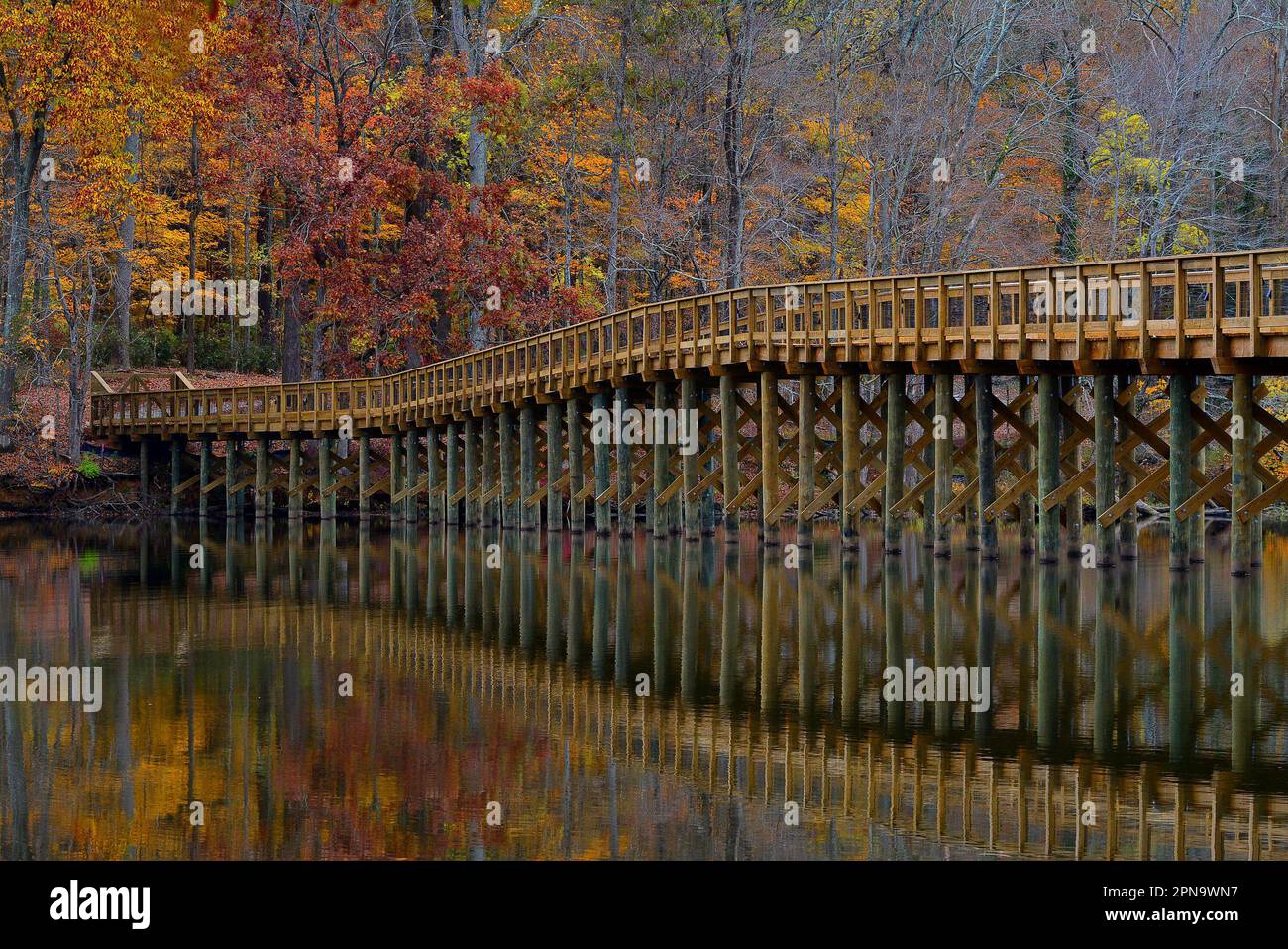 Bridge over still lake with fall colors Stock Photo - Alamy