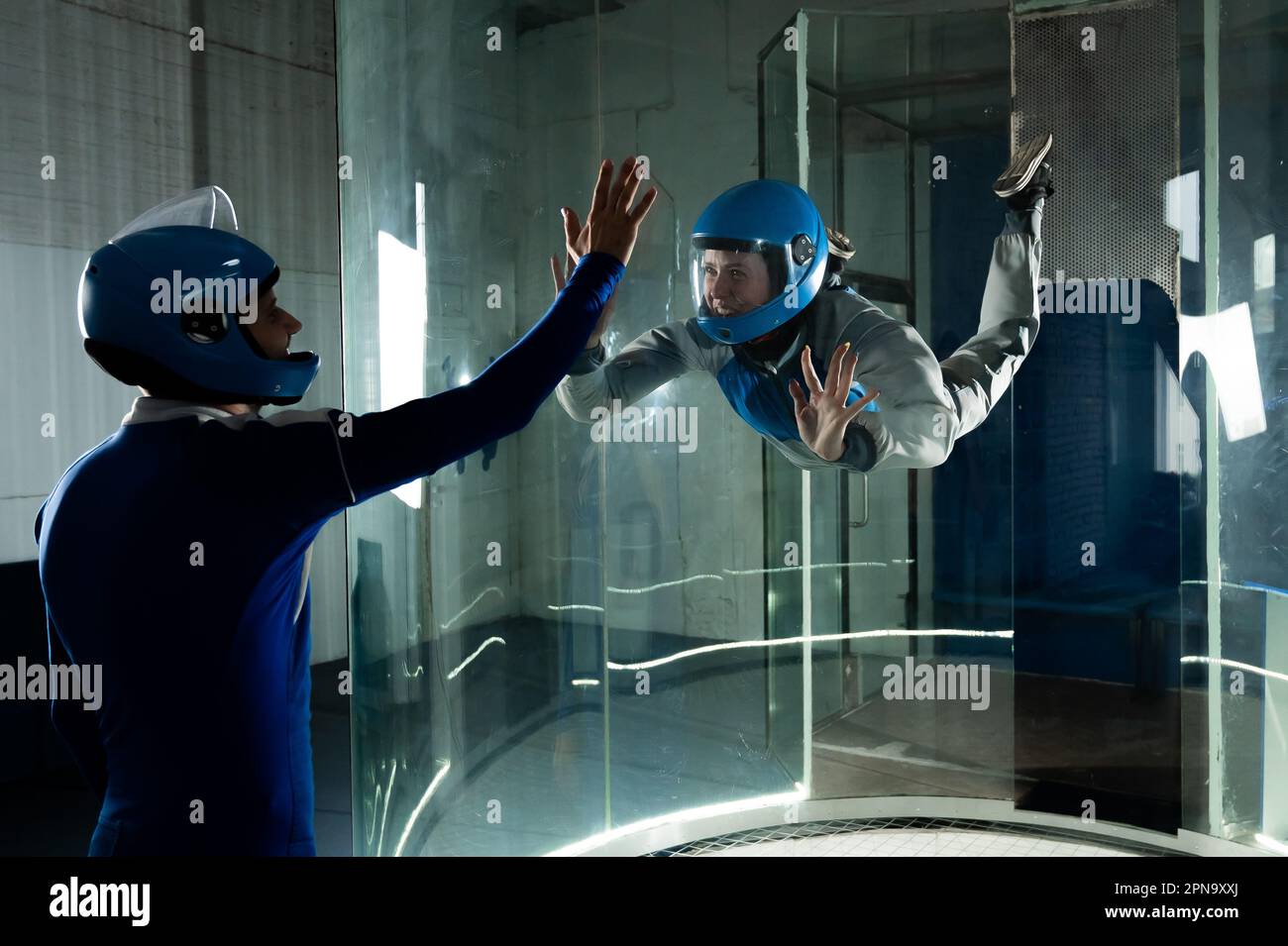 A male instructor teaches a woman how to fly in a wind tunnel. Free ...