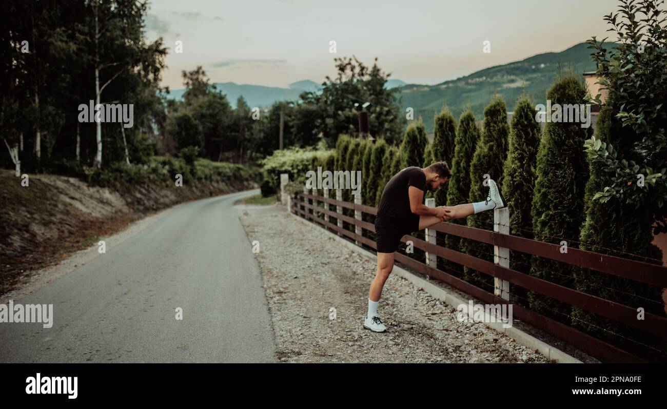 Athlete performing leg stretching exercises after a run in a natural ...