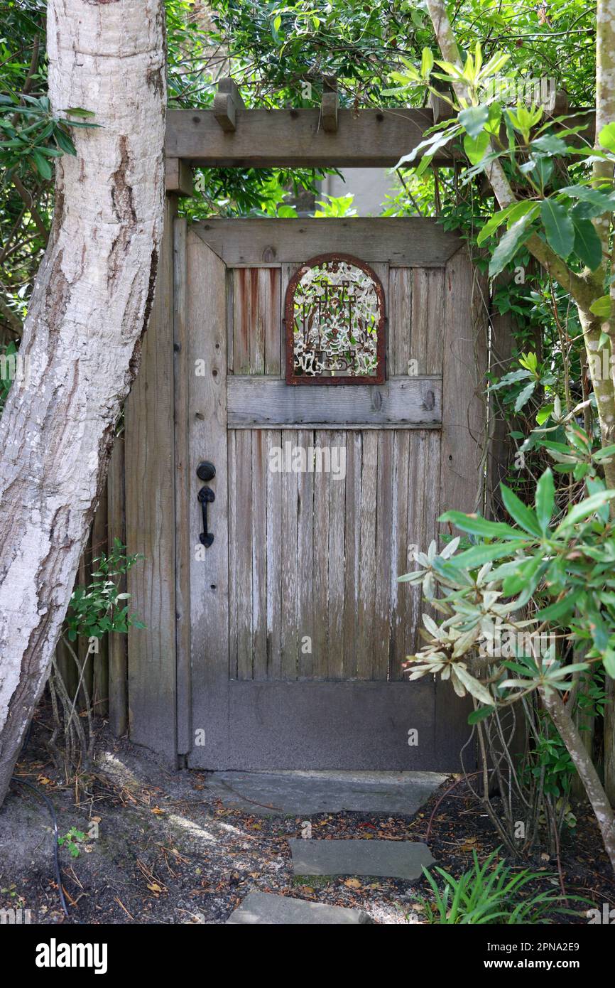 Garden entry gate with dense foliage provides a charming entrance to a ...