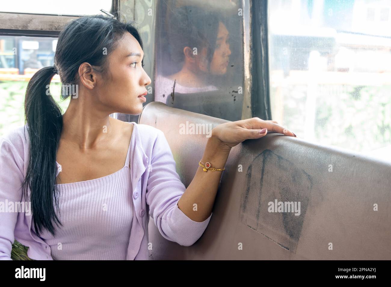 A young woman sits in a old bus and looks back through the rear window ...