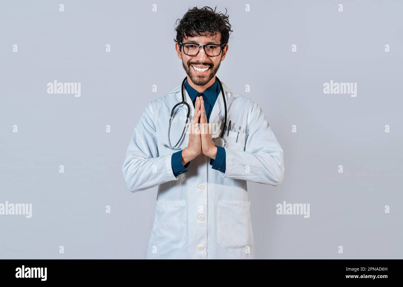 Young doctor with palms together. Smiling doctor putting palms together ...