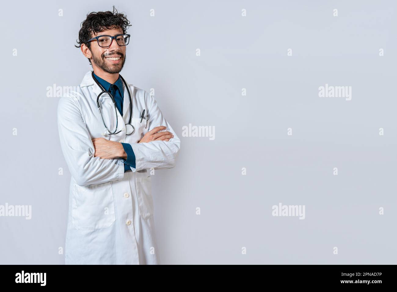 Smiling doctor with crossed arms on isolated background. Latin doctor ...