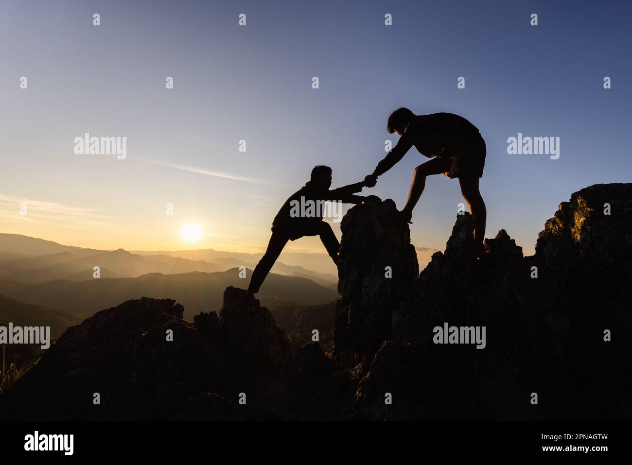 Silhouette Teamwork, Male hikers climbing up mountain cliff and one of ...