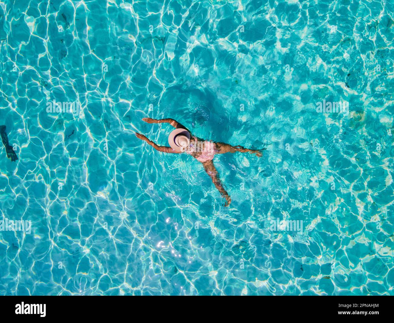 drone view of a Asian woman swimming in the blue turqouse colored ocean ...