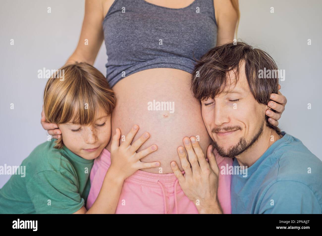 Father and elder son listen to mom's pregnant belly Stock Photo - Alamy