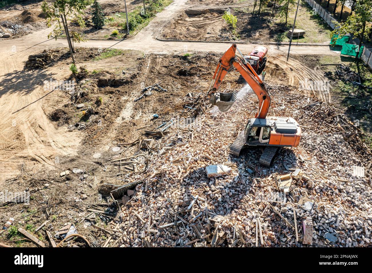 excavator working on pile of debris from a dismantled building at a demolition site. aerial view ...