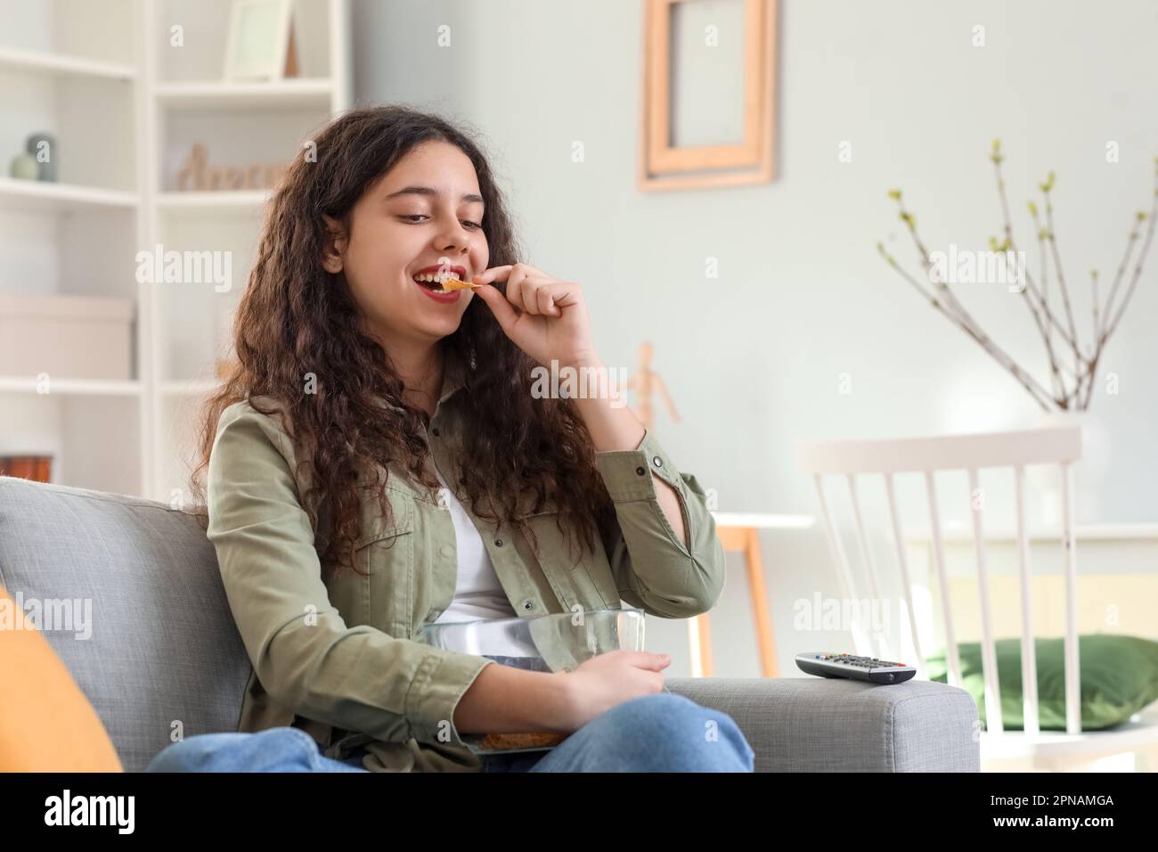 Teenage girl eating tasty chips at home Stock Photo - Alamy