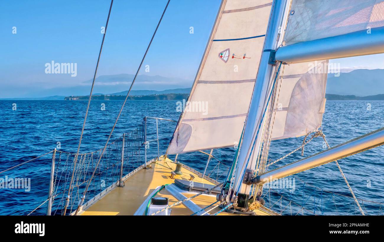 Coastal sailing, viewed from the foredeck of a sailboat with the jib ...