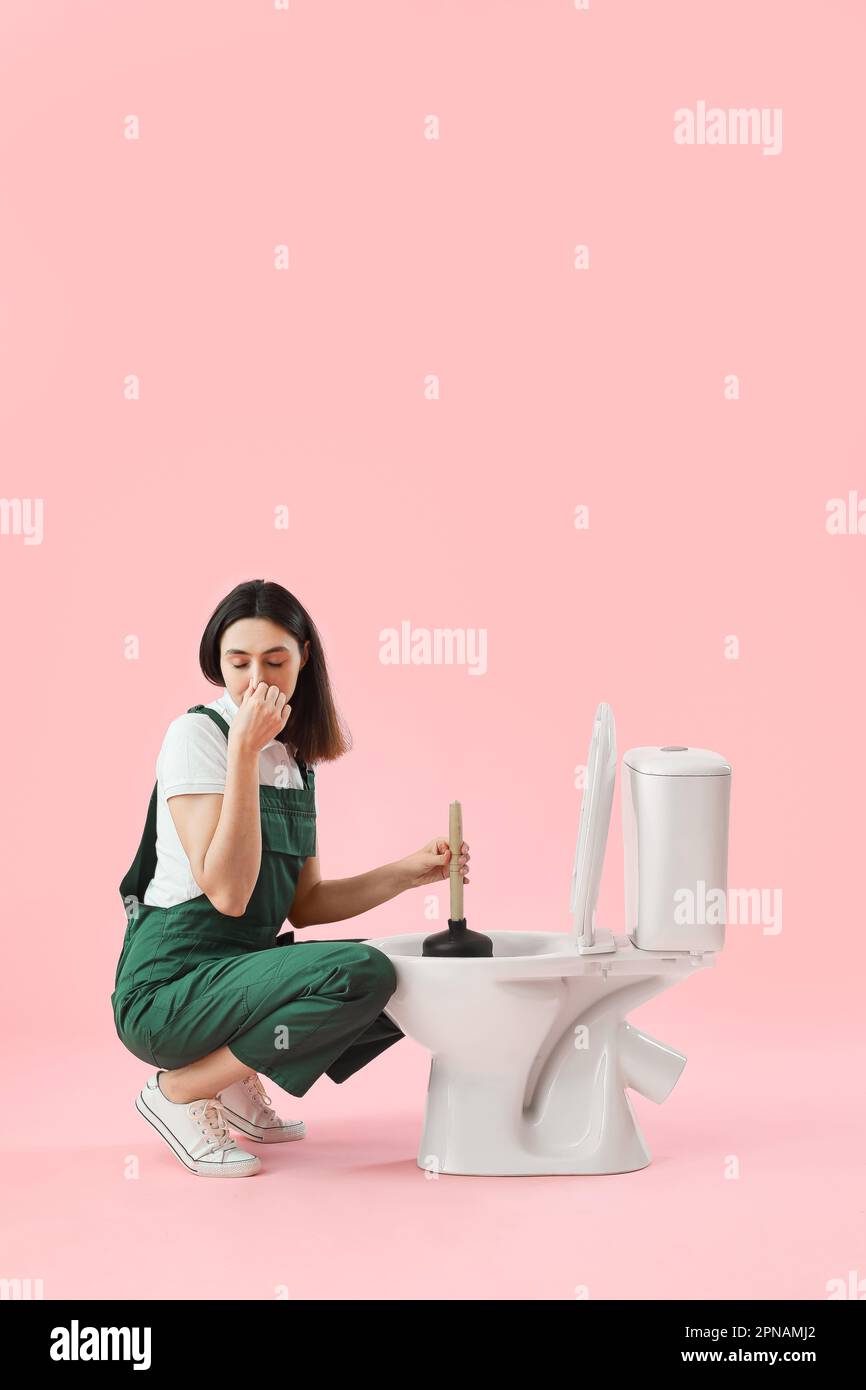Female plumber with plunger and toilet bowl on pink background Stock ...