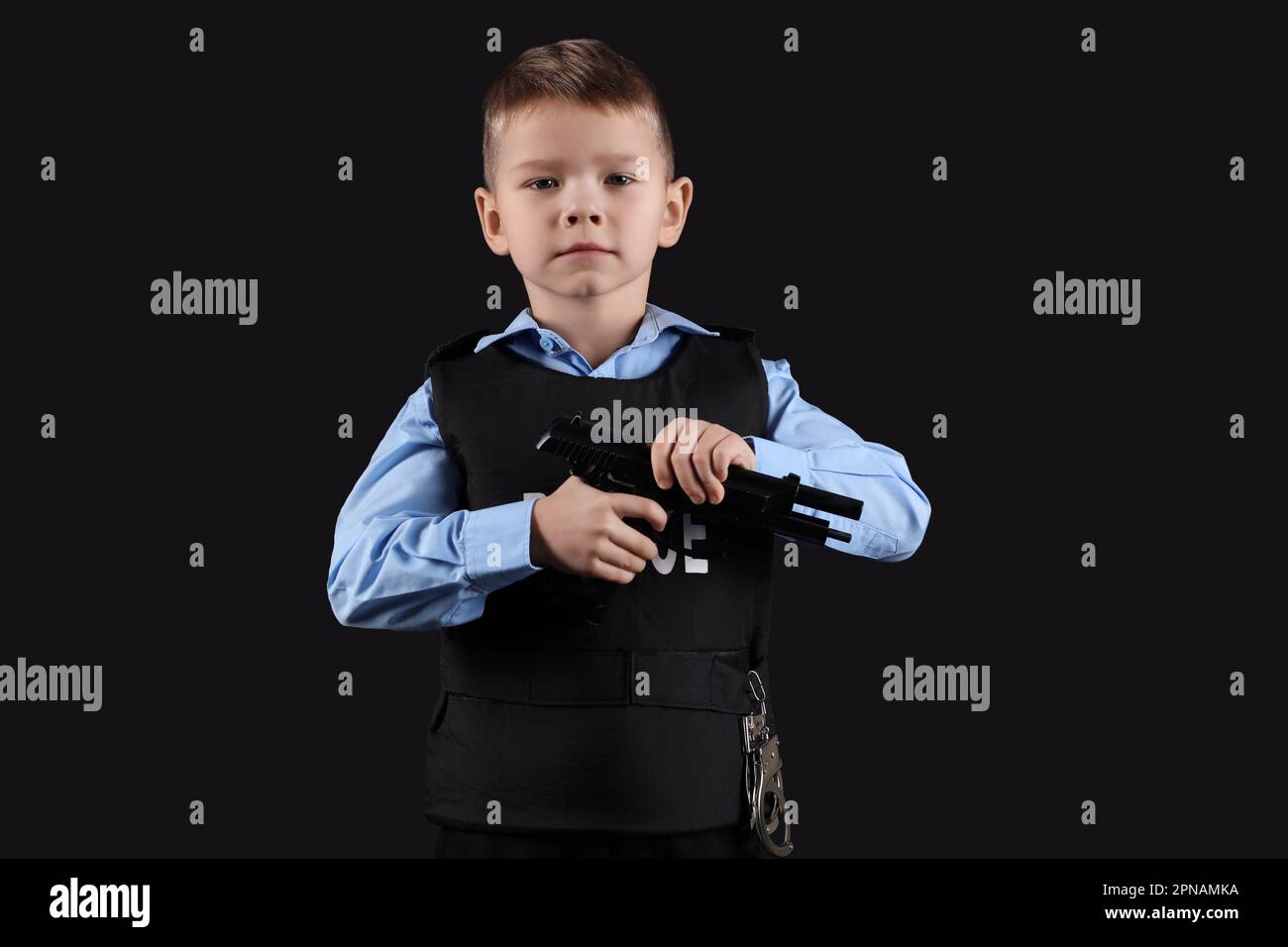 Cute little police officer with gun on black background Stock Photo - Alamy