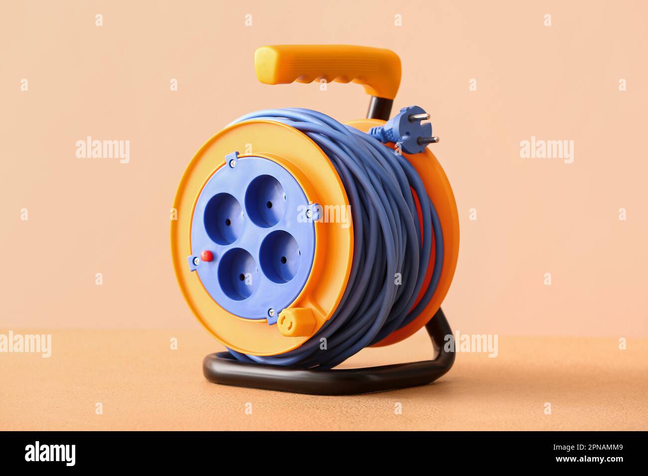 Extension electric cable reel near color wall Stock Photo - Alamy