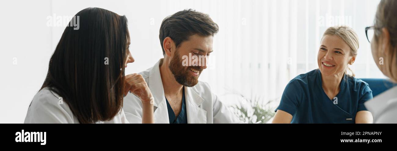 Group of doctors sitting at meeting table in conference room during ...