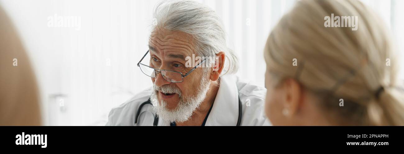 Group of doctors sitting at meeting table in conference room during ...