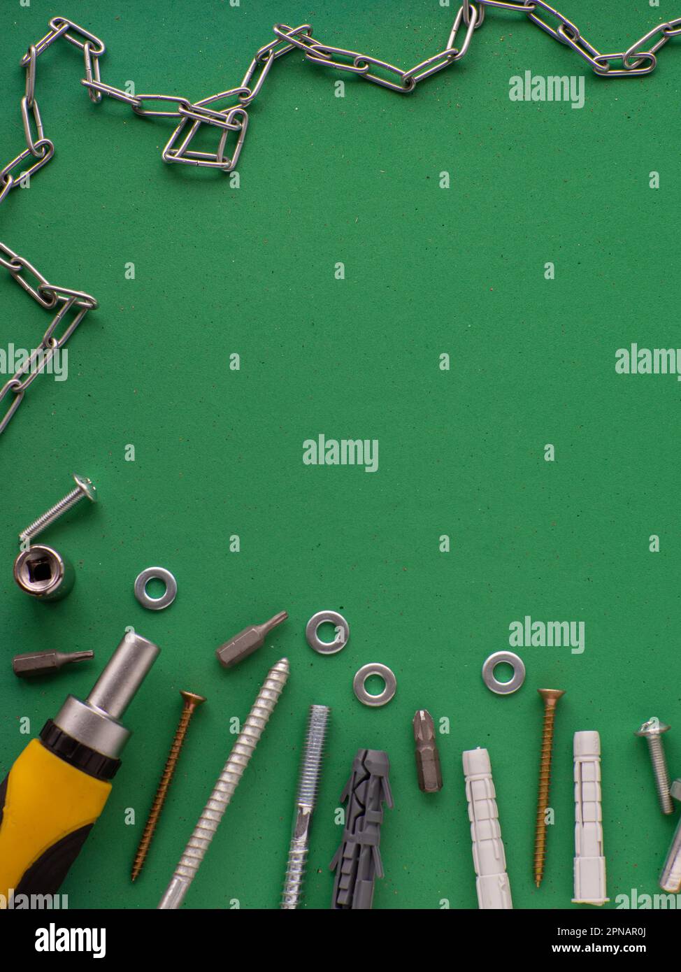 Green background with hand tools, metal chain, fasteners and fittings ...