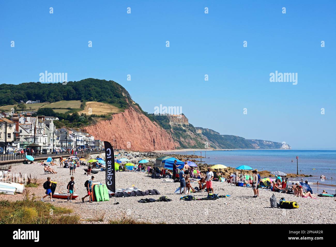 Tourists relaxing on the beach with views towards town buildings and ...
