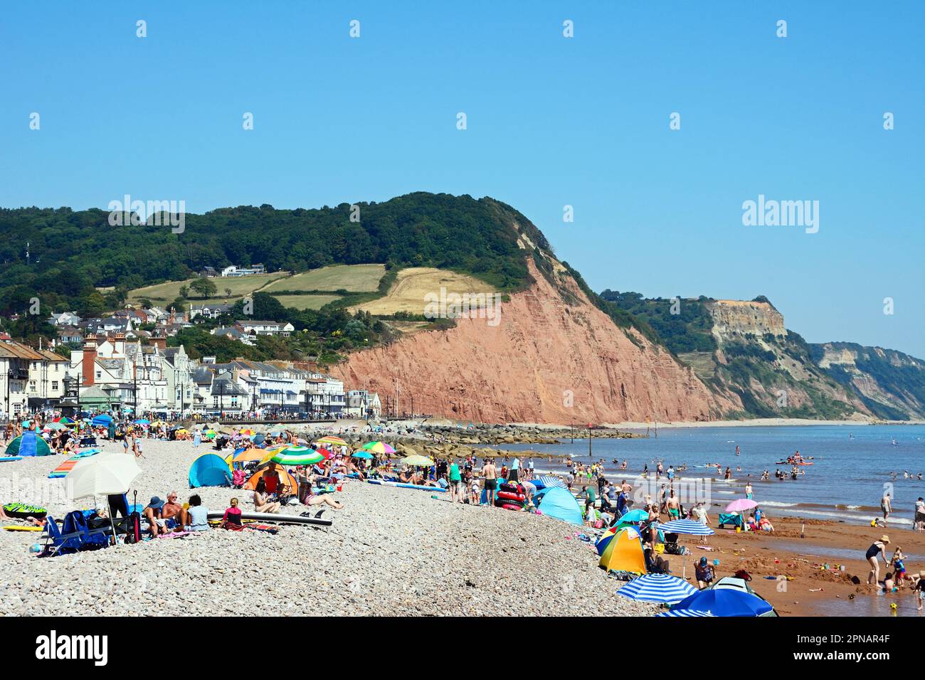 Tourists relaxing on the beach with views towards town buildings and ...