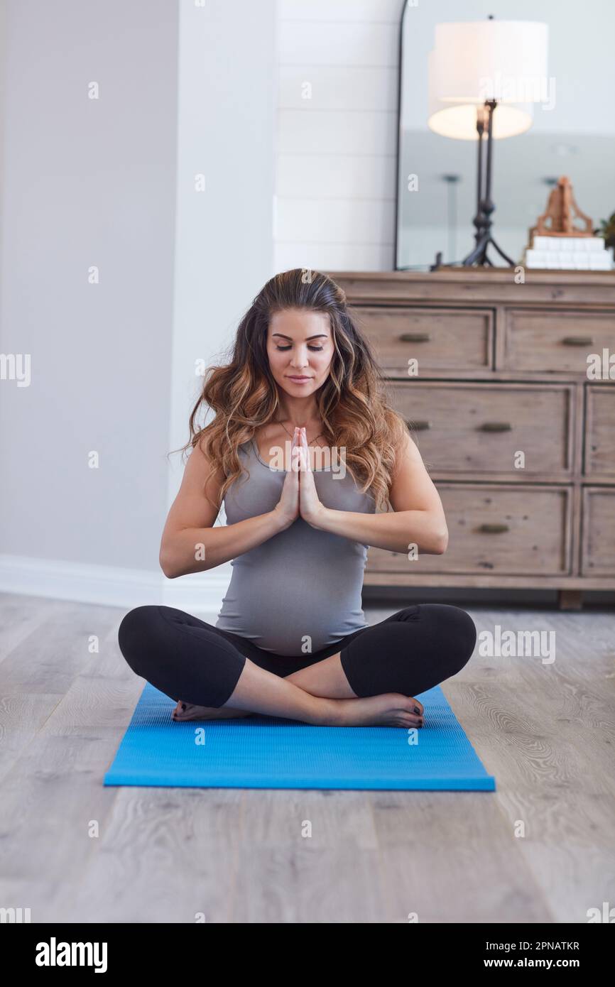I am calm, my baby is calm. a pregnant young woman meditating at home ...