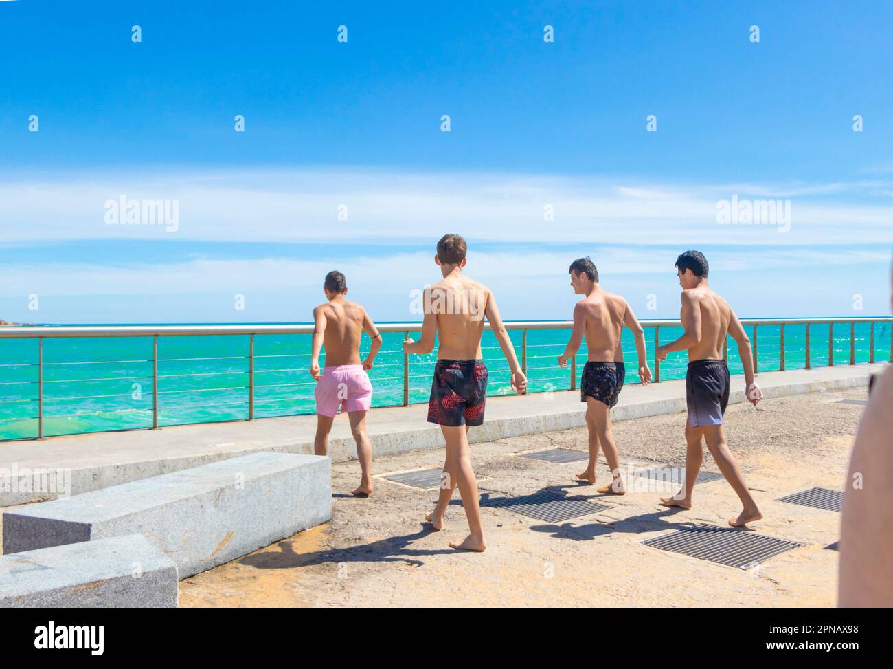 four teenage boys in swim shorts on a pier in albufeira algarve ...