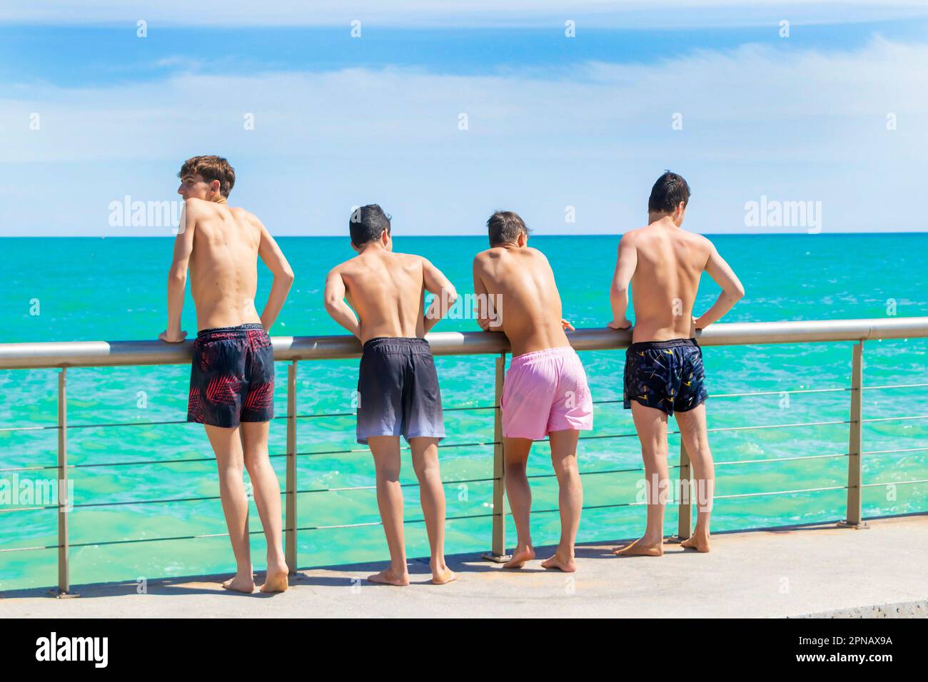 four teenage boys in swim shorts on a pier in albufeira algarve ...