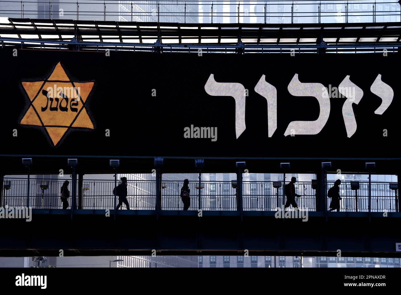 People walk along a bridge lit with a billboard showing a yellow Star ...