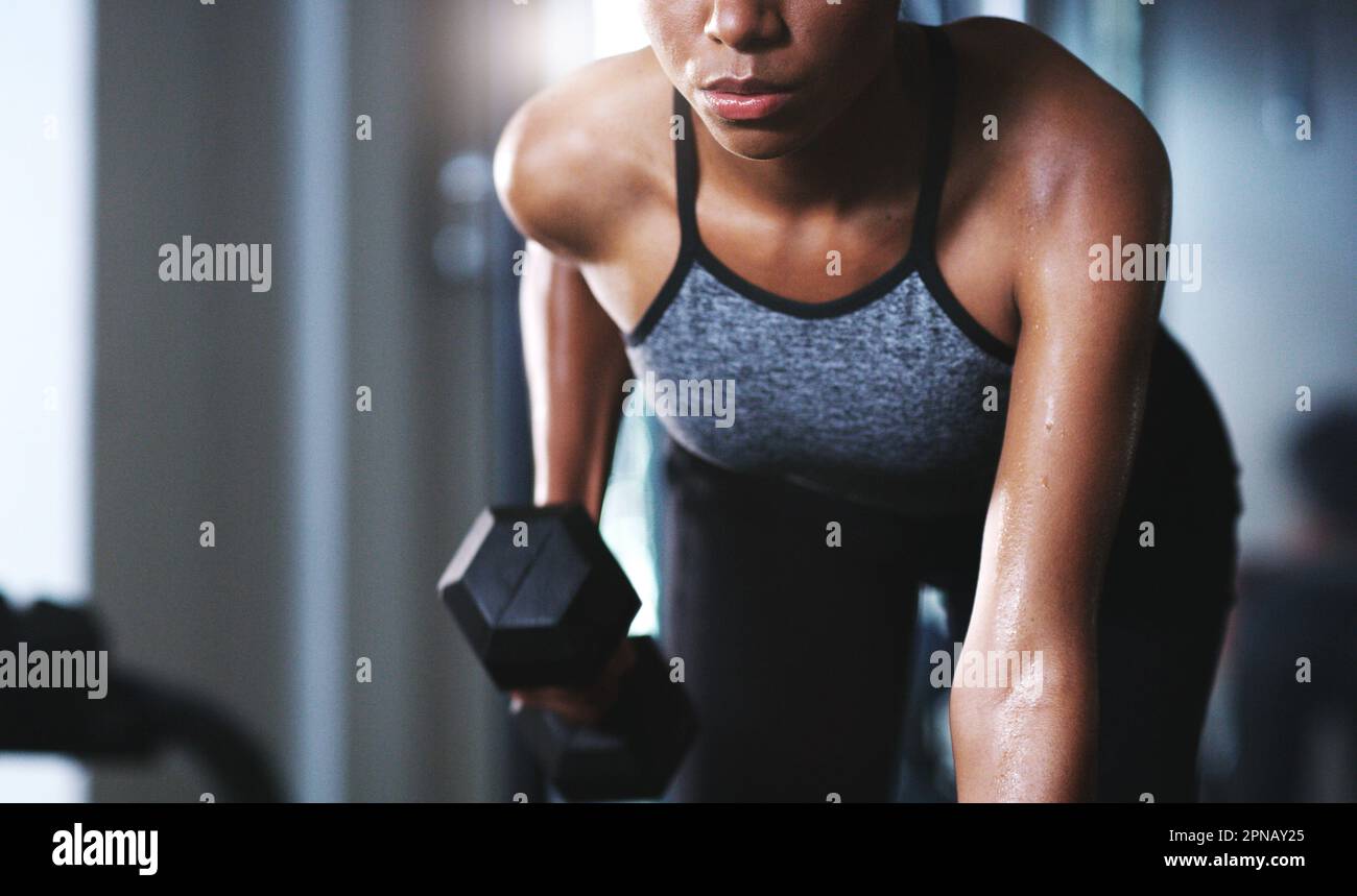 Dont wish for a good body, work for it. a sporty young woman exercising with a dumbbell at the ...