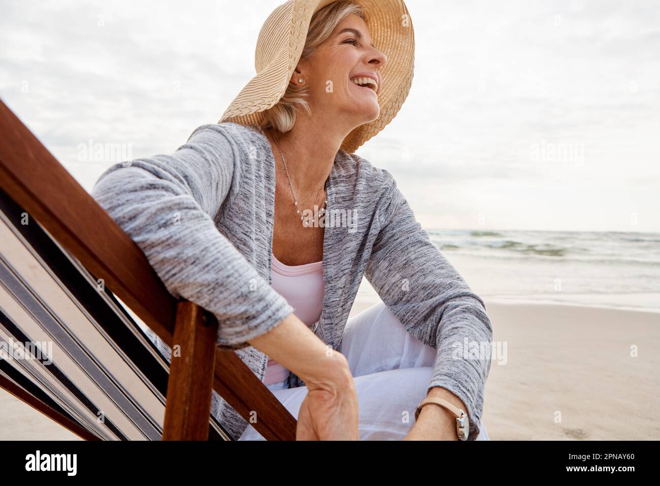 Shes all smiles at the beach. an attractive middle aged woman sitting ...