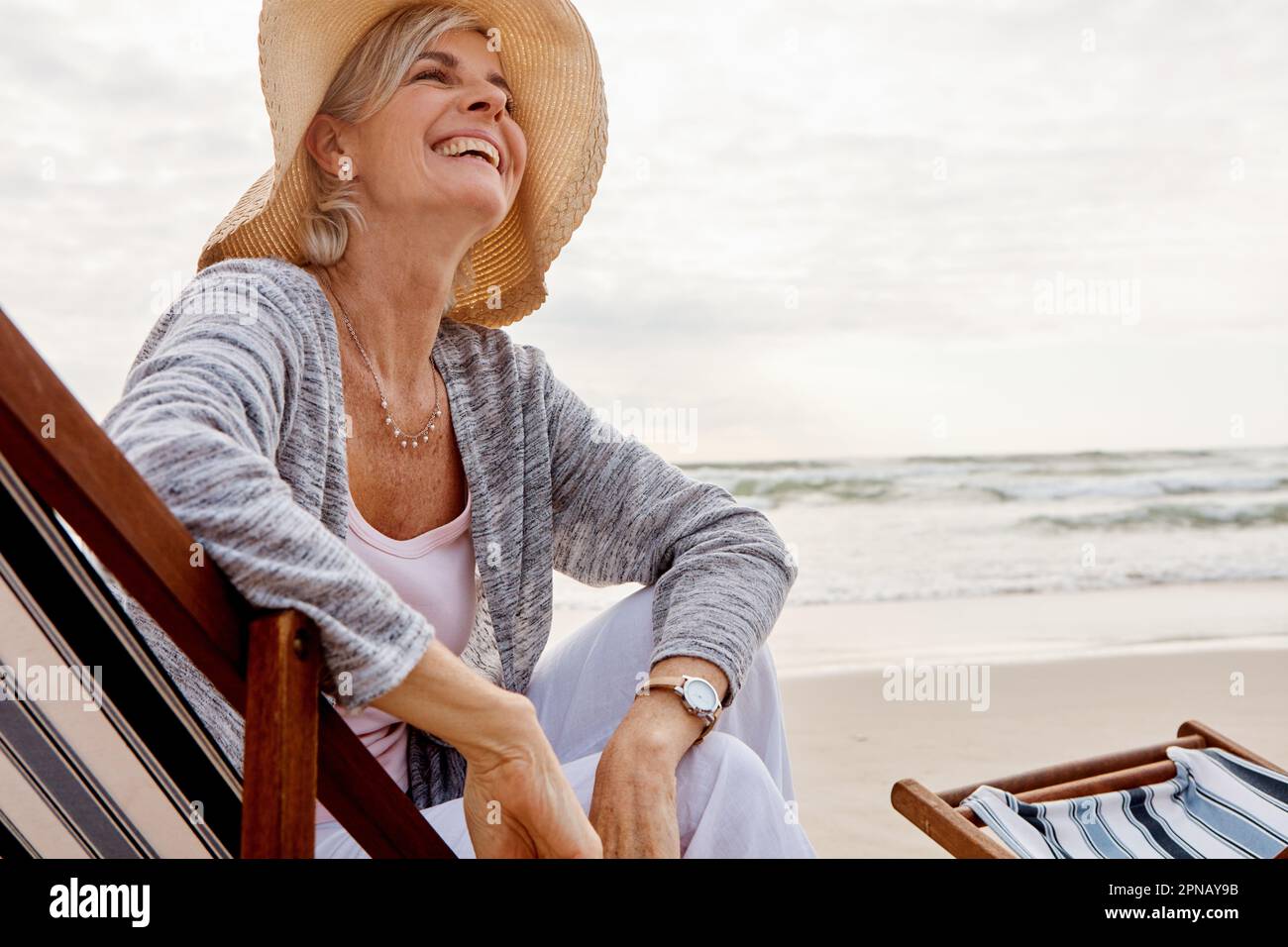 The beach is full of beauty. an attractive middle aged woman sitting on ...