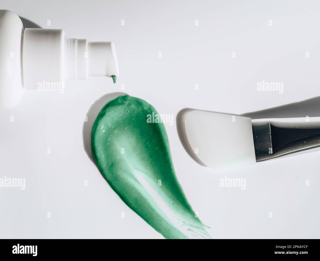 facial mask smeared from jar with dispenser with makeup brush on white ...