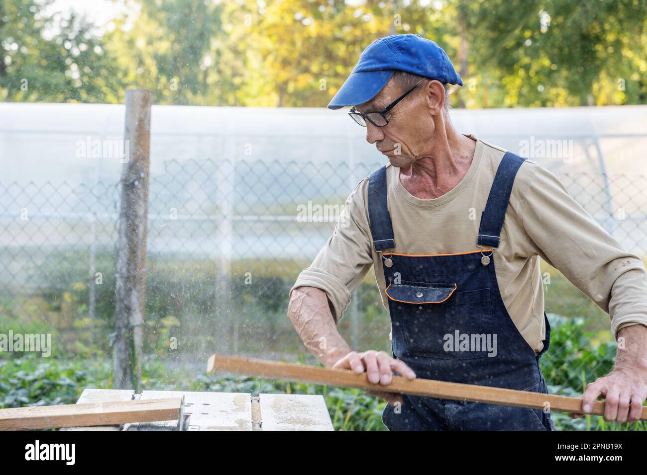 a carpenter processes wooden planks while on the street on a country ...